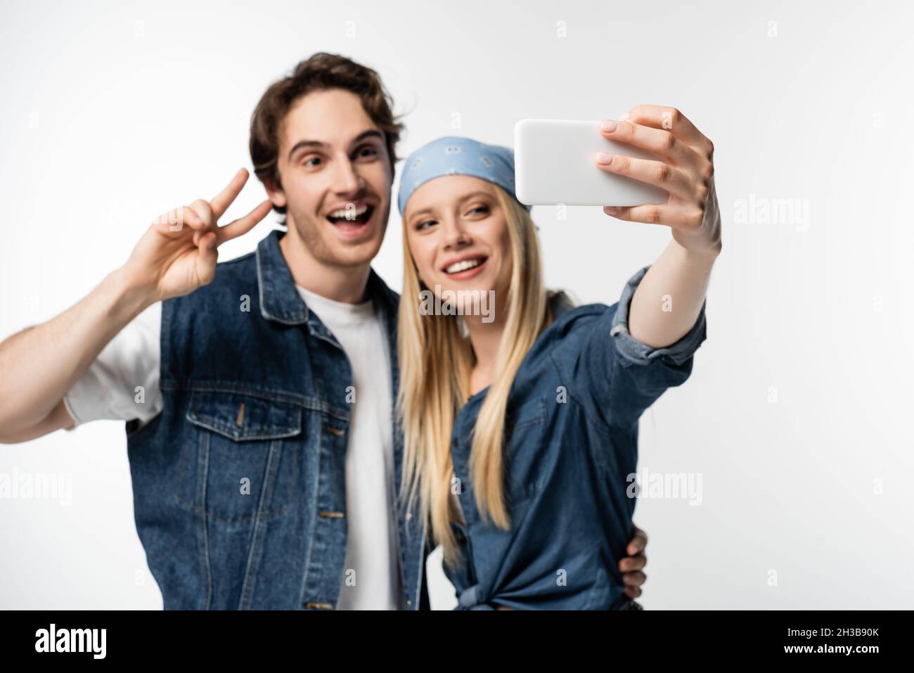 happy woman taking selfie with boyfriend showing peace sign on blurred ...