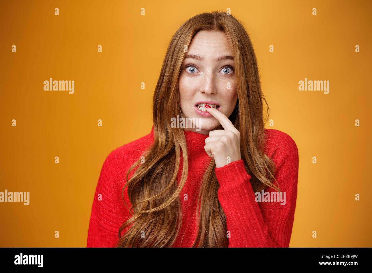 Silly, cute redhead woman making innocent oops expression holding ...