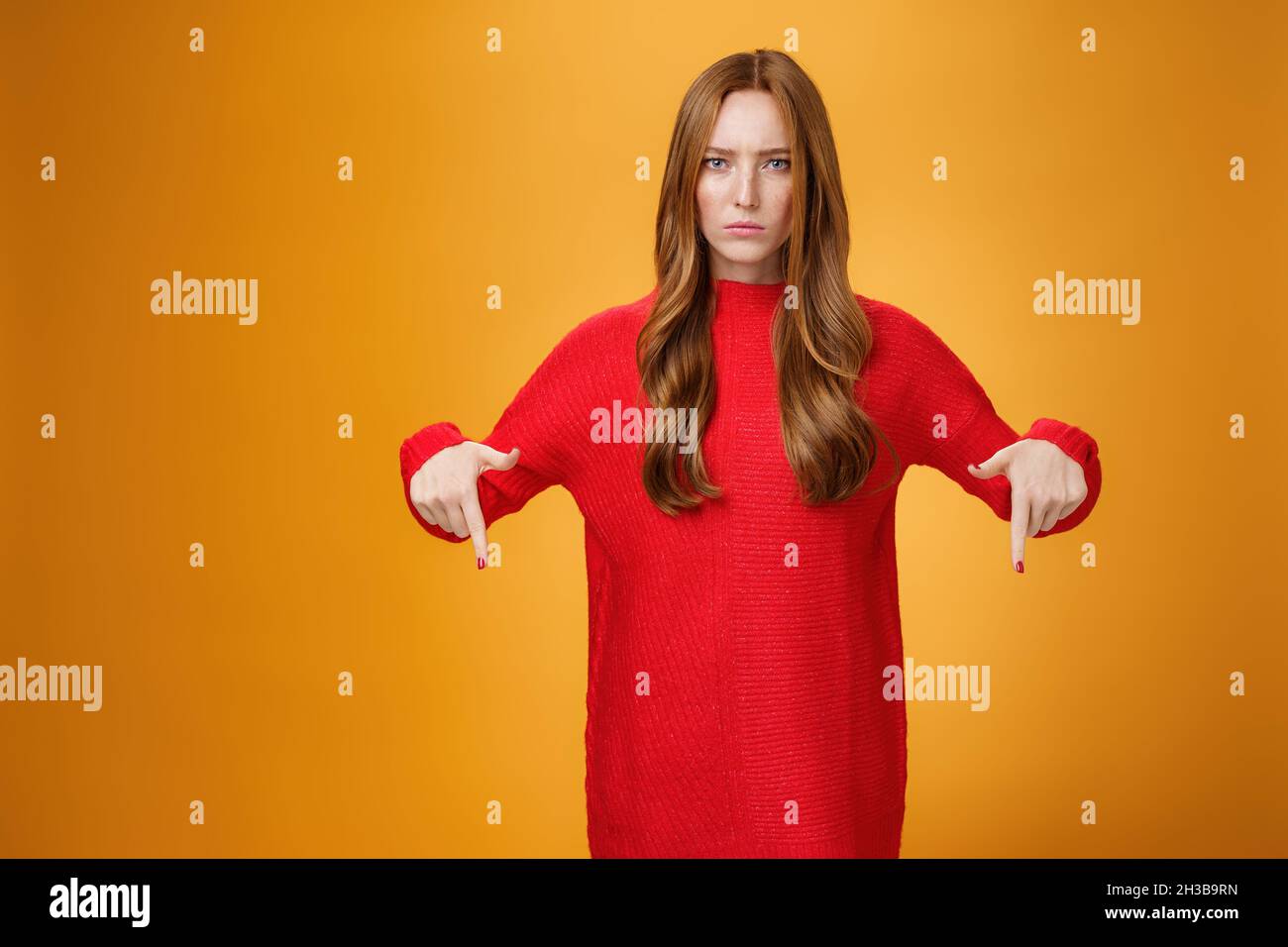 Displeased serious-looking female in knitted red dress frowning looking ...