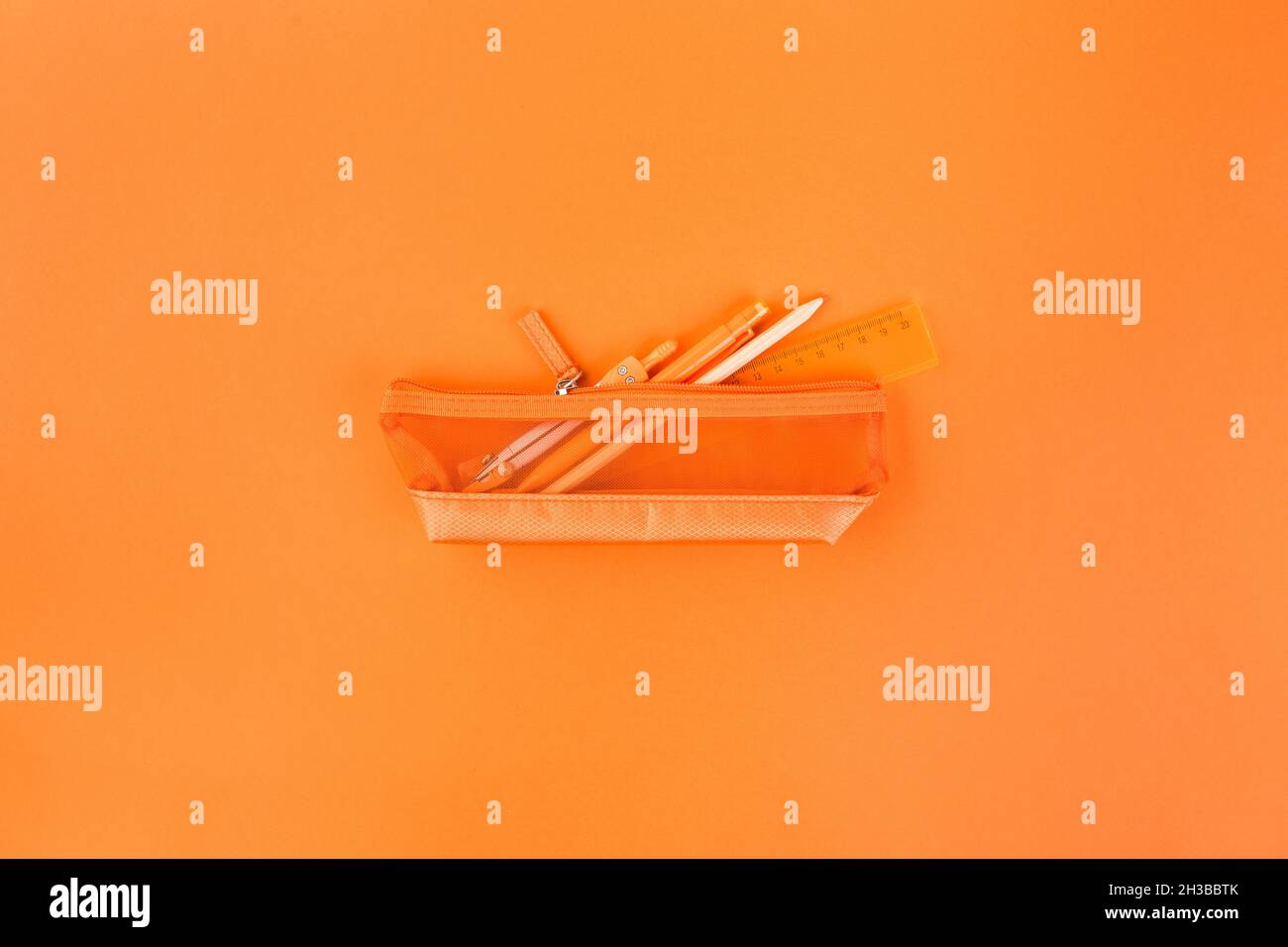 Different orange school supplies in case on orange table. Back to ...