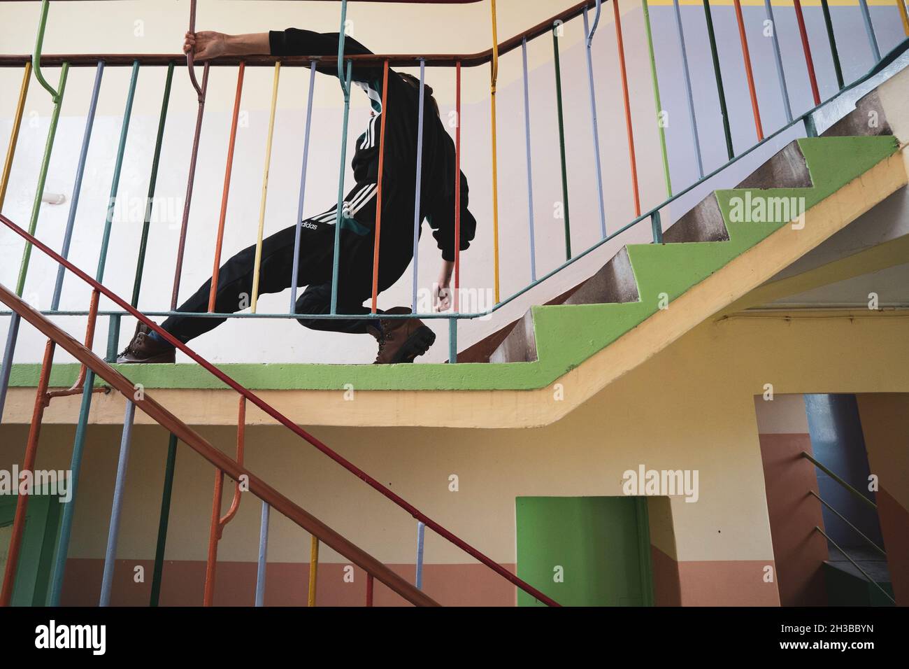 athletic androgynous strong woman hangs off bars in pastel school Stock ...