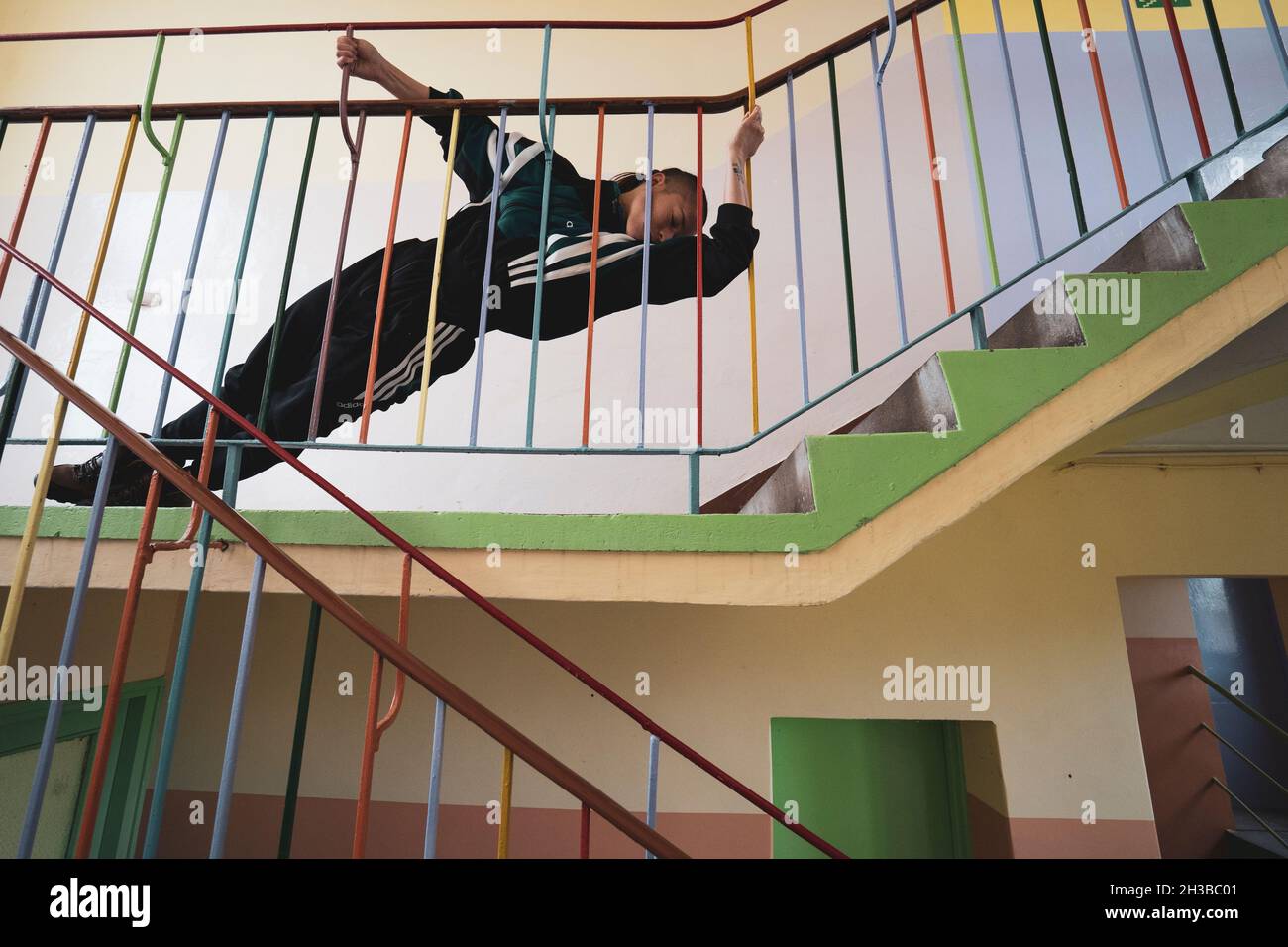 athletic androgynous strong dancer hangs off bars in pastel school ...