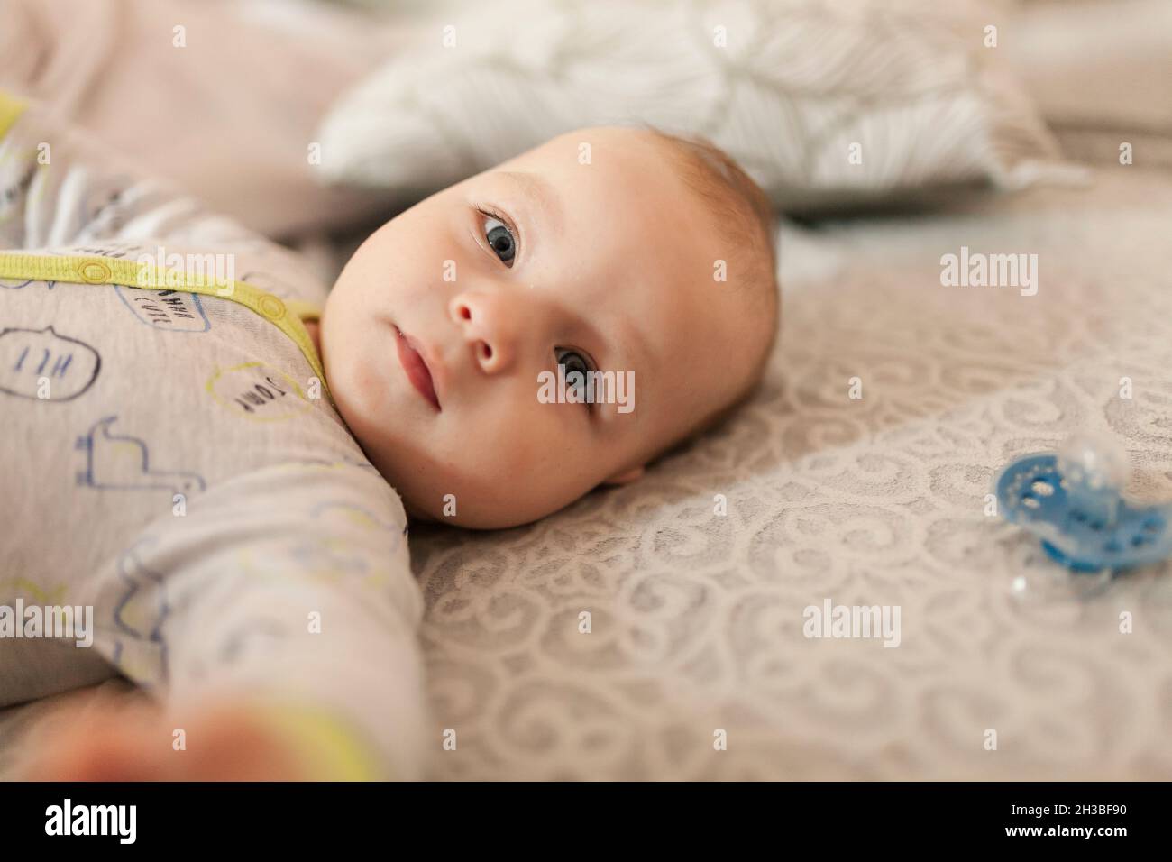 Ifant boy lying down on bed next to him is blue dummy Stock Photo - Alamy