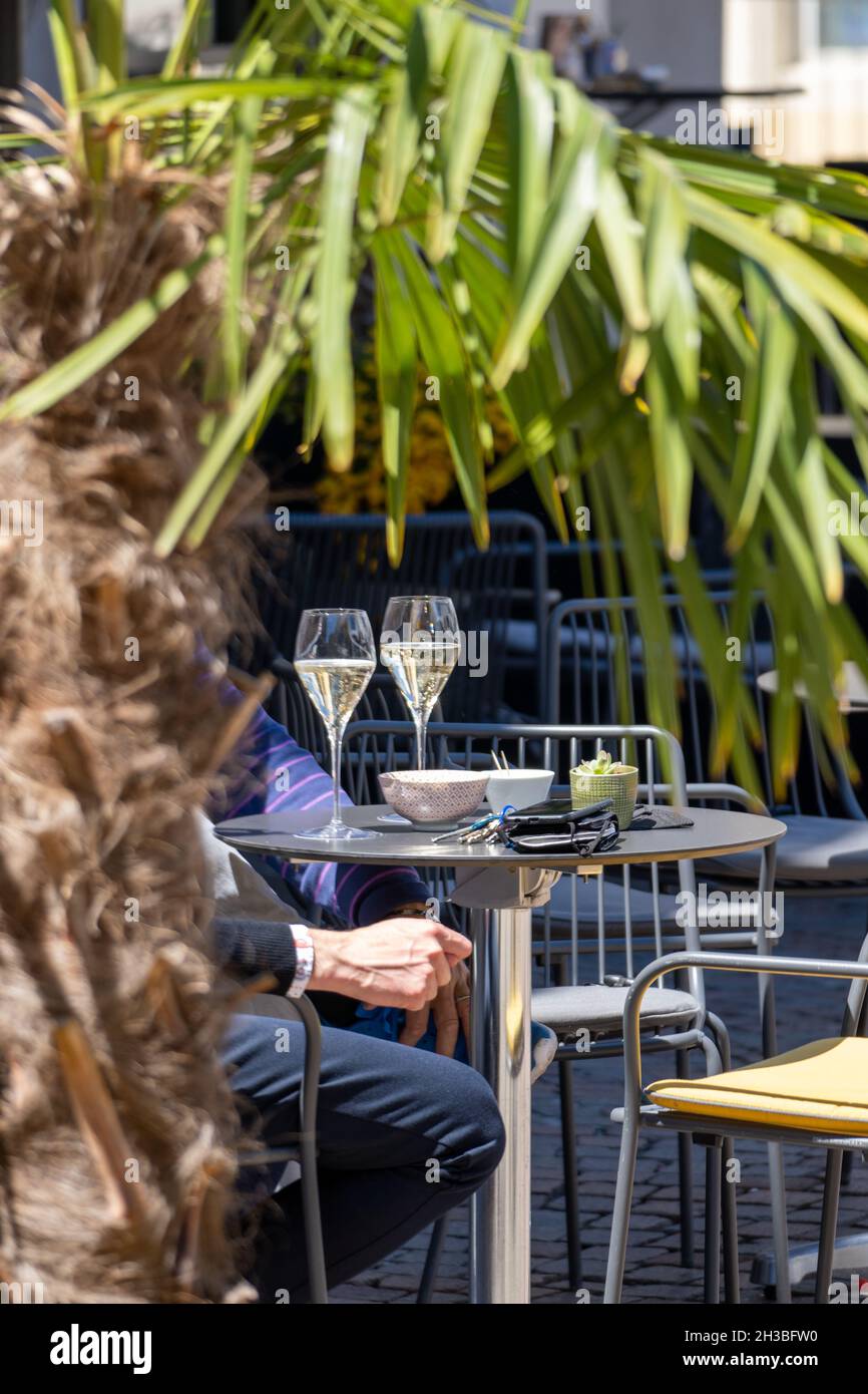 Vertical shot of two people at a cafe table with two glasses of ...