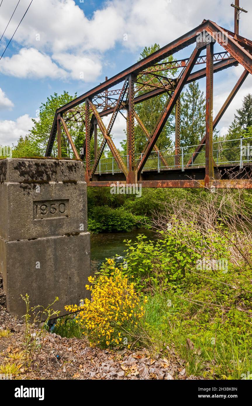 Small, rusty old girder bridge, apparently finished in 1950, over water ...