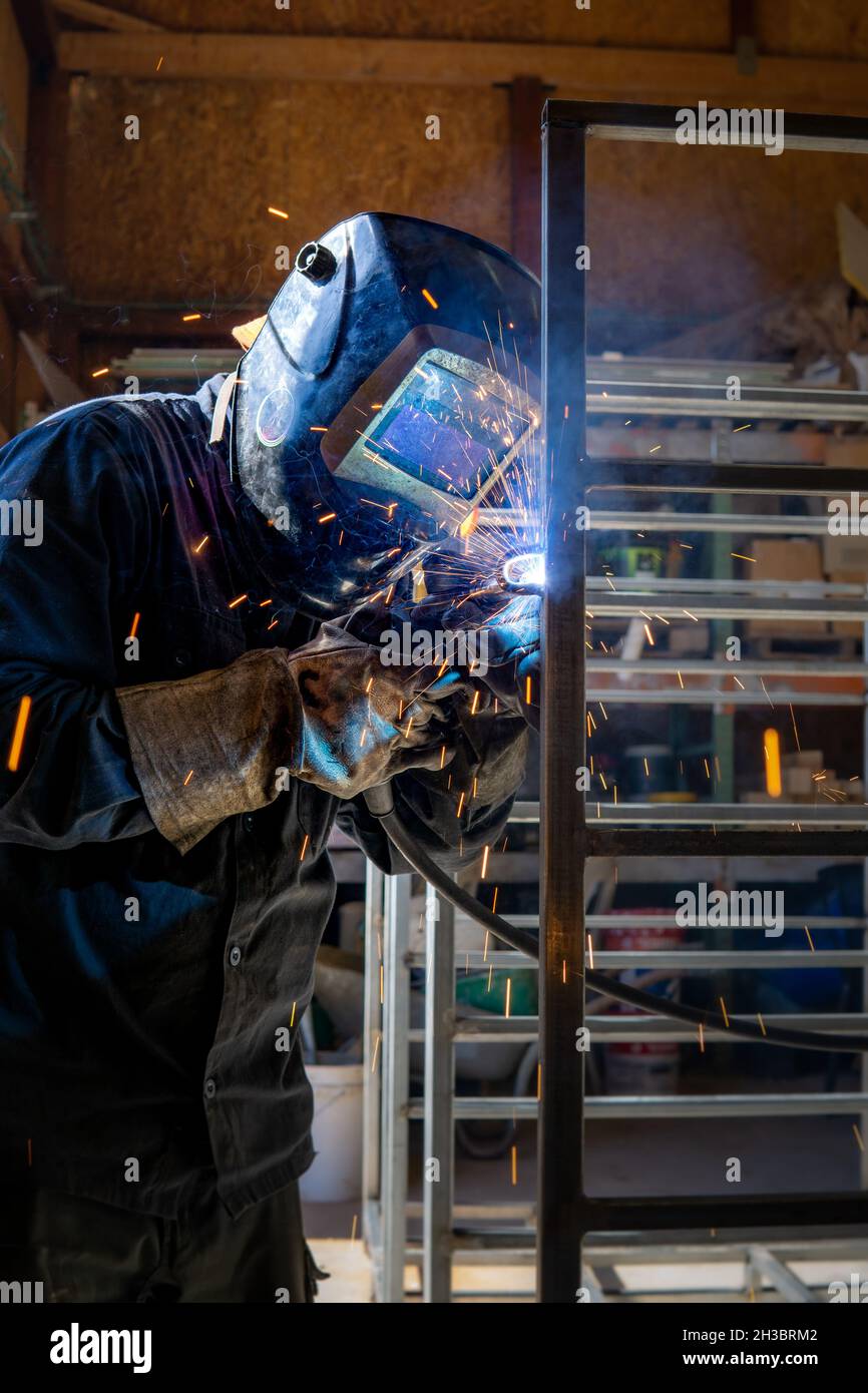 Worker with protective mask welding metal cage in kibbutz ravid, israel ...