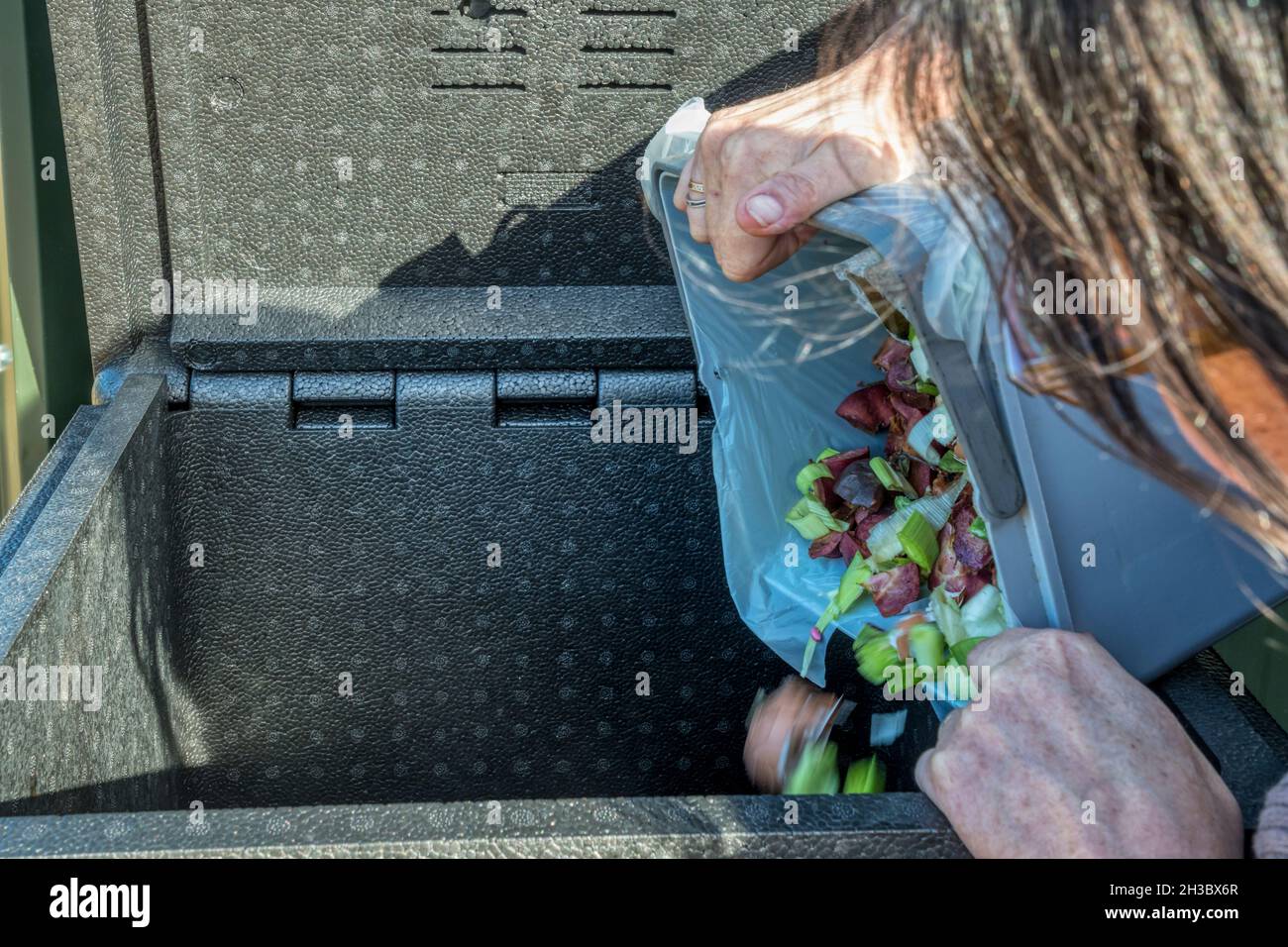 Tipping contents of recycling caddy, including cooked food, into hot ...