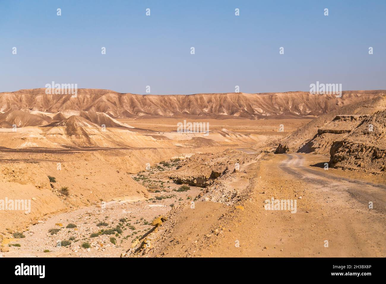 Rocky Mountains in Israel next to gravel dusty and unpaved road through the arid dry Judean ...