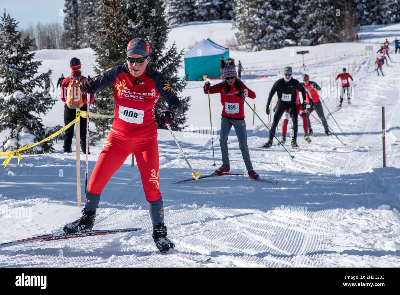 A long line of cross country skiers race across a snowy valley in the ...