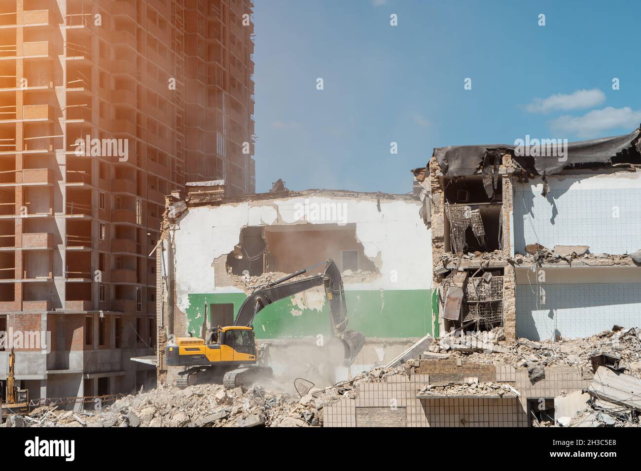 demolition old building by excavator near new construction of modern ...
