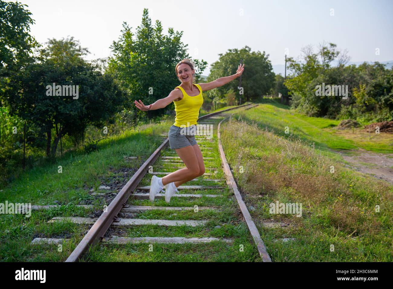 beautiful girl jumping on the railroad tracks Stock Photo - Alamy