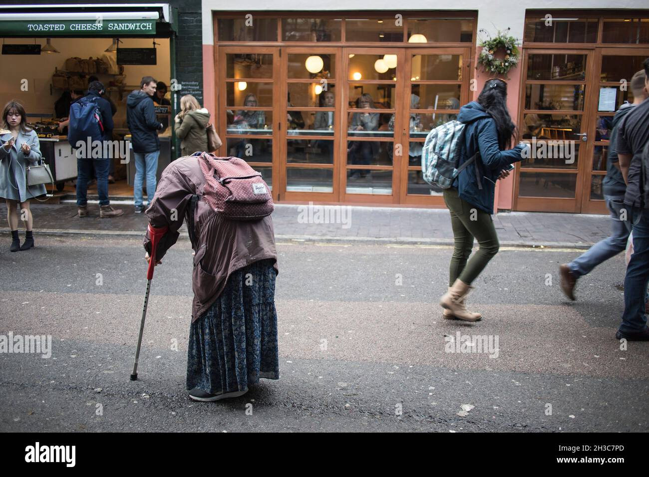 London, UK - 20 November 2020, A beggar woman walks through the crowd ...