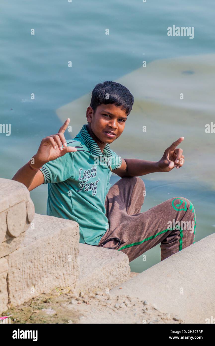 VARANASI, INDIA - OCTOBER 25, 2016: Local boy sits at a Ghat riverfront ...