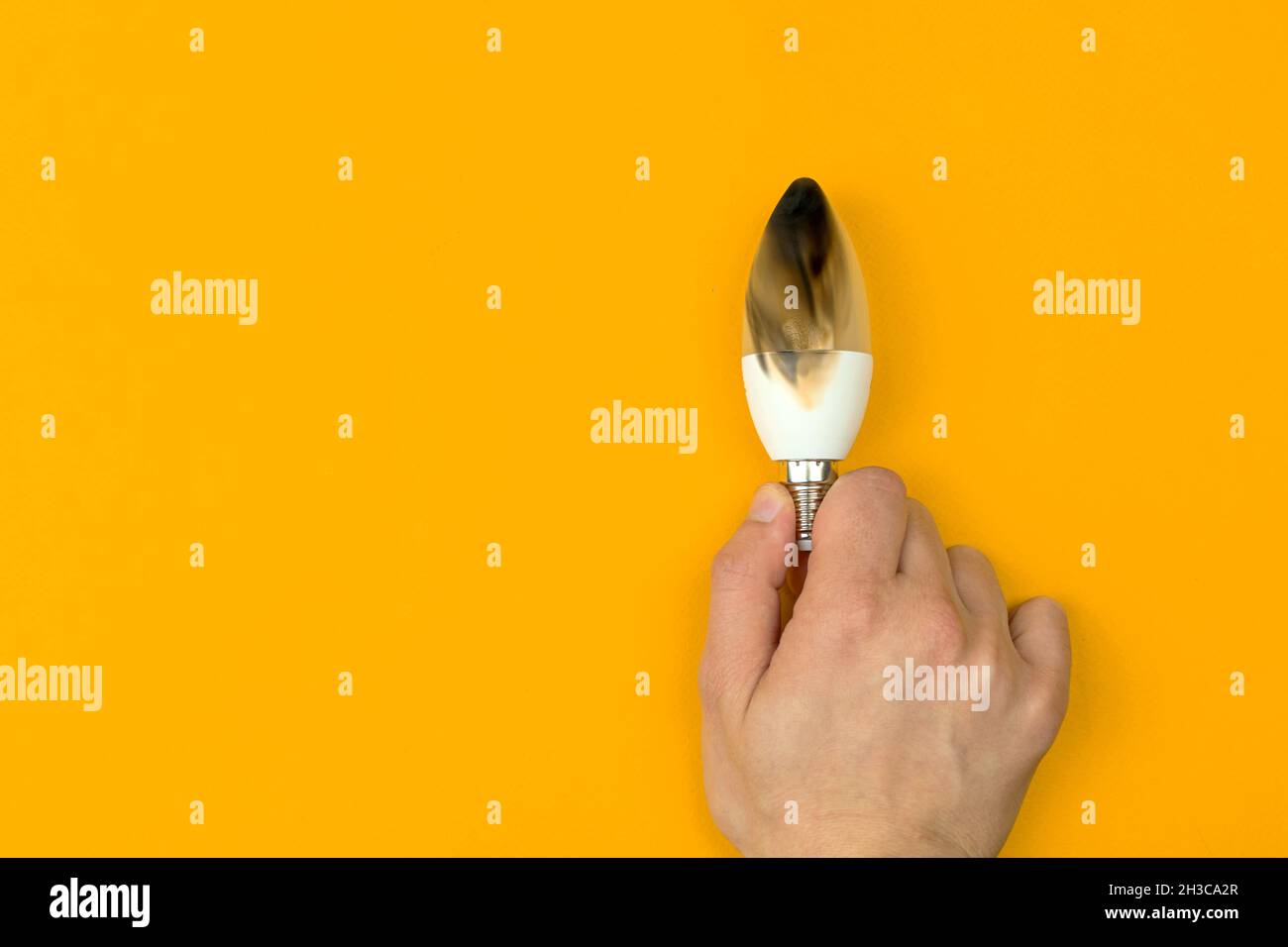 Hand with burned LED light bulb. Concept of electrical short circuit ...