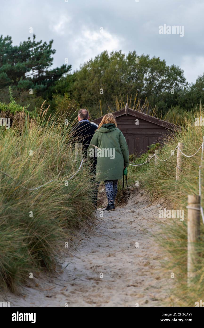 middle aged man and woman walking along a sandy path in the countryside ...