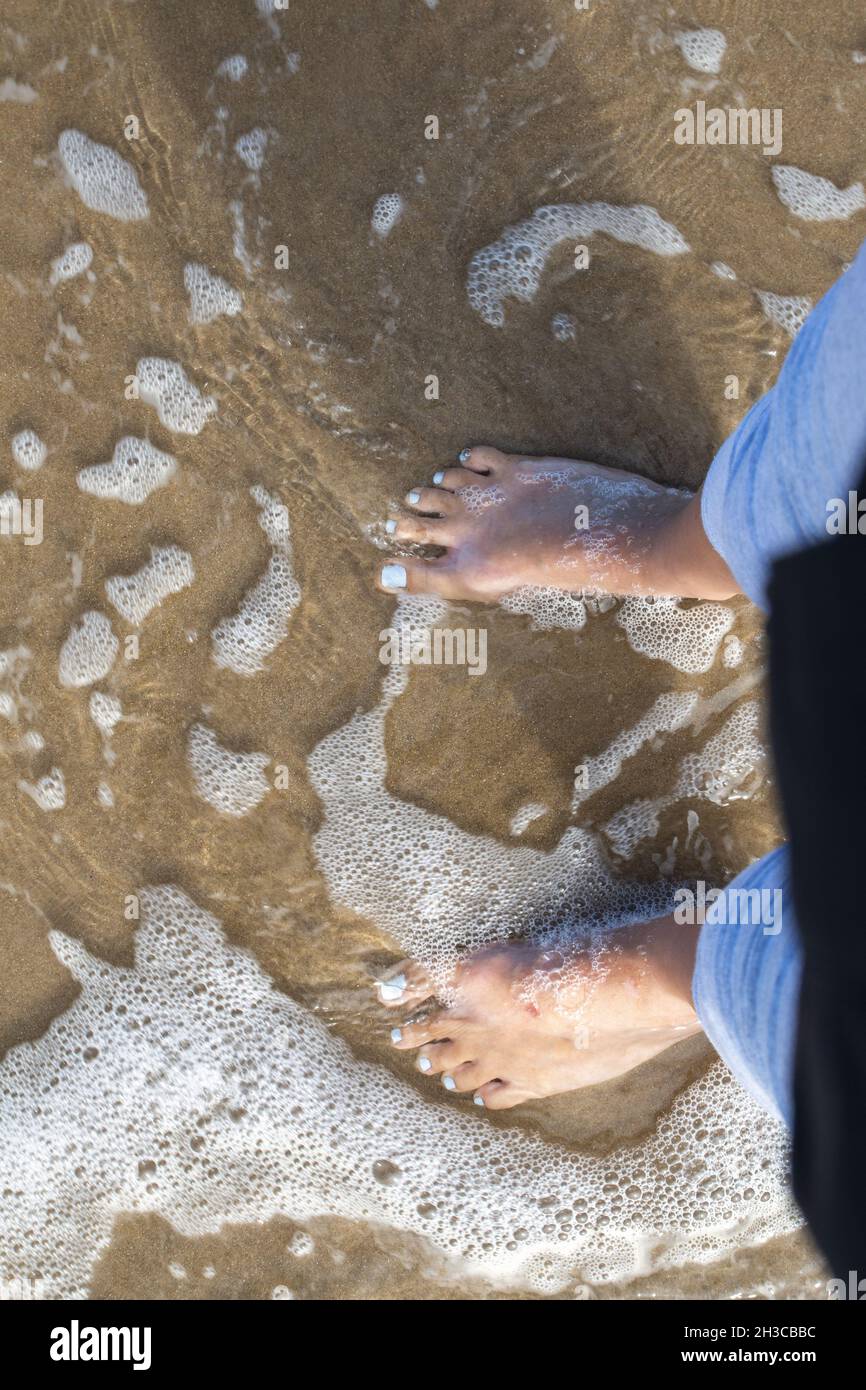 High angle shot of a female's feet at a beach being washed off by the ...