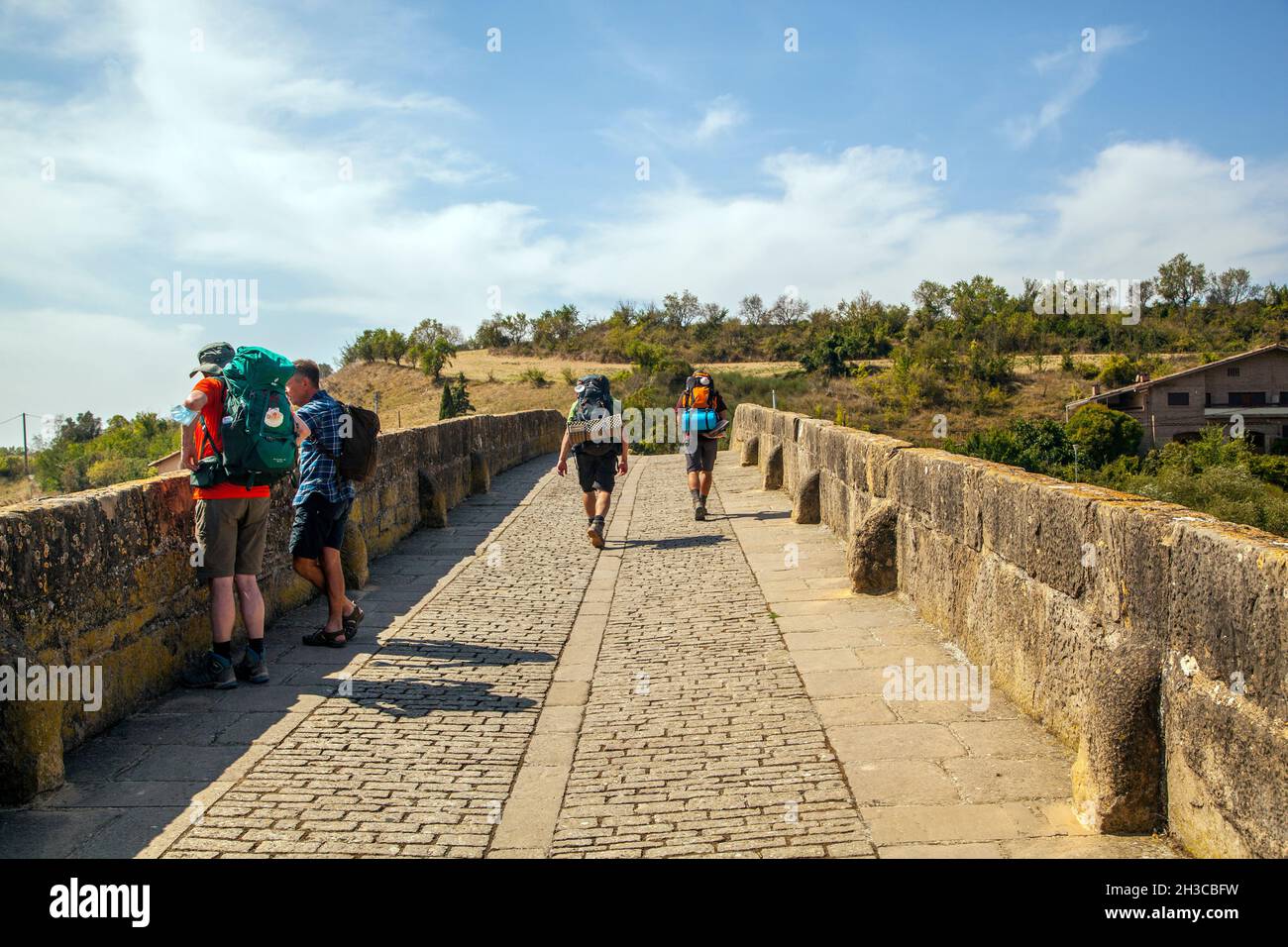 Pilgrims walking over the Puente Romanico medieval bridge in the ...