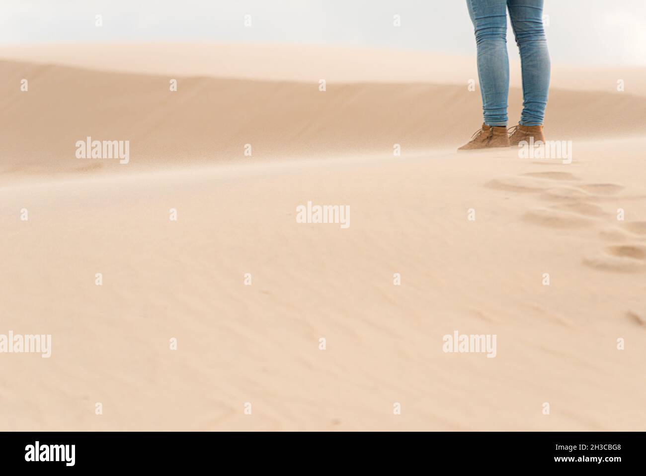 Person standing in sand dunes. Wind blowing sand away Stock Photo - Alamy