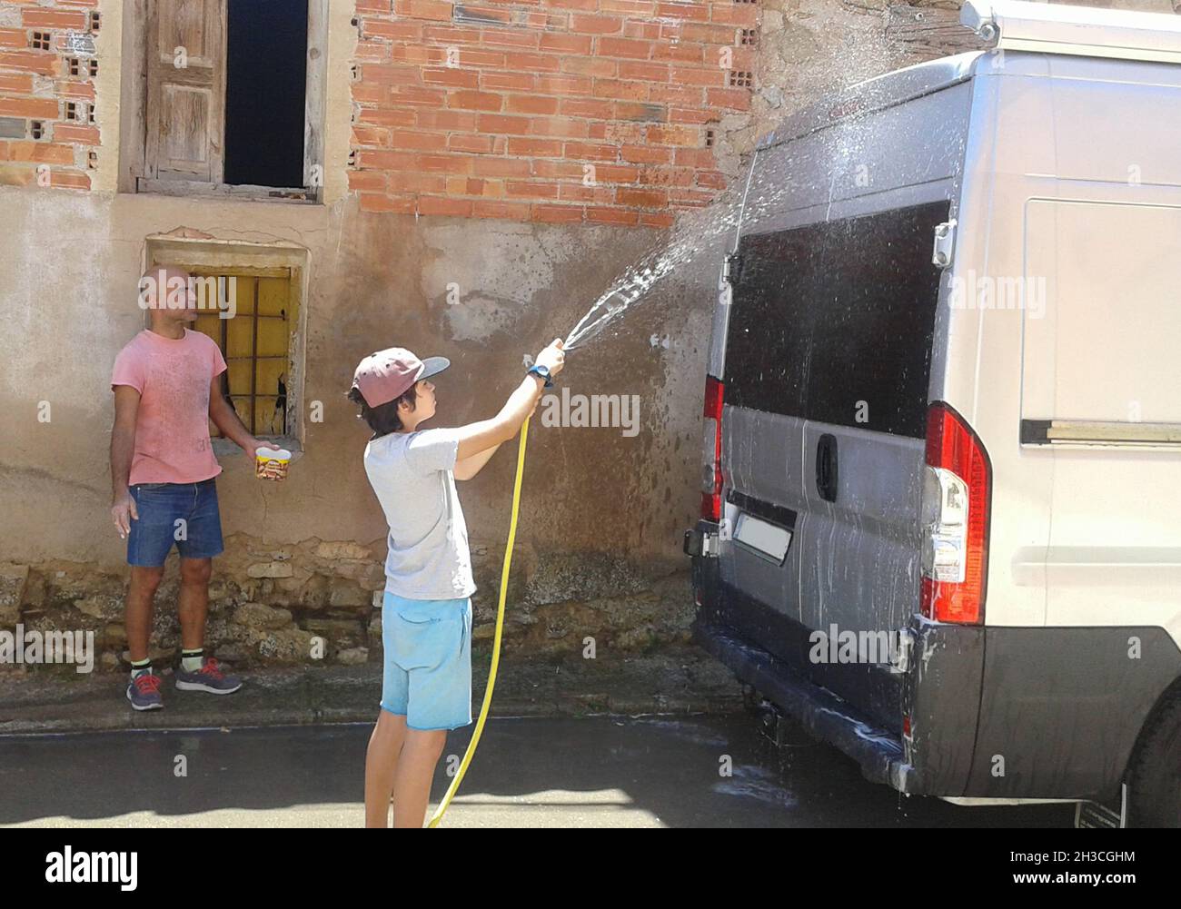 Man and a boy washing a car with water from a hose Stock Photo - Alamy