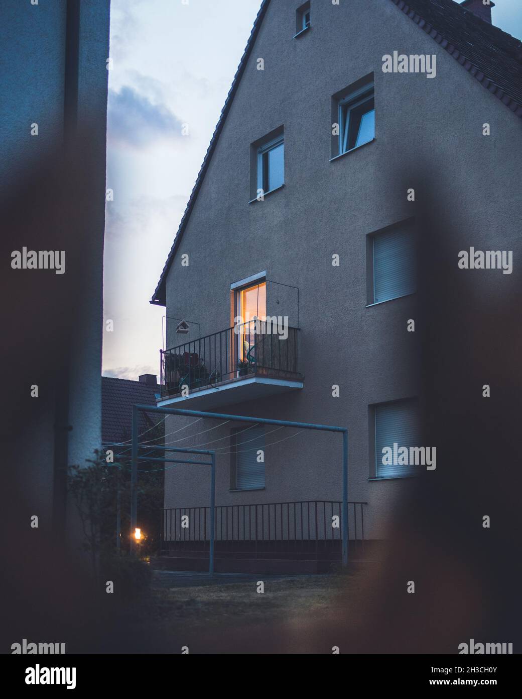View through the fence on a building with a balcony and light on Stock ...
