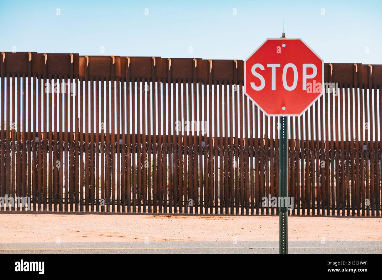 a stop sign in front of the steel US-Mexico border wall in the town of ...