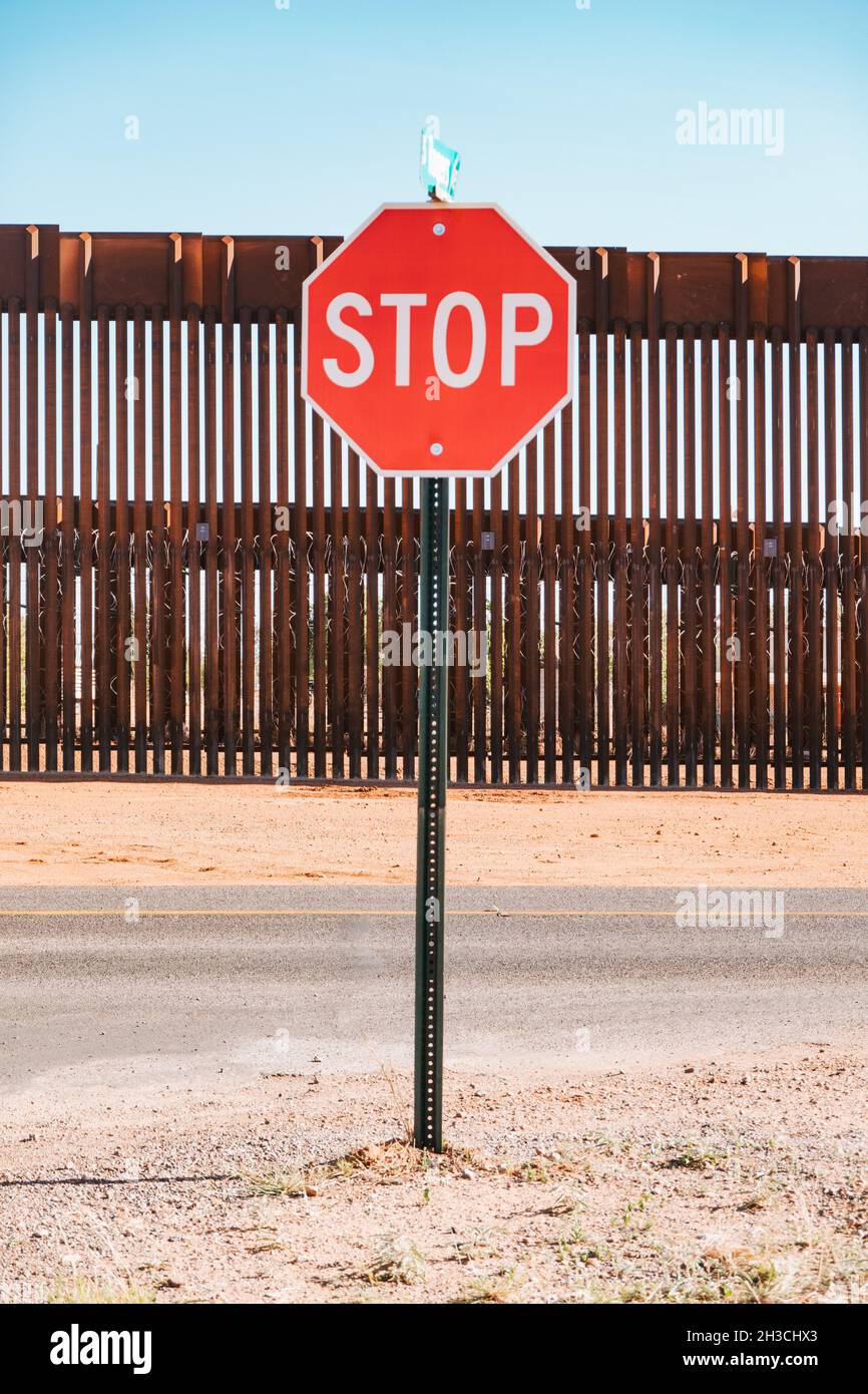 a stop sign in front of the steel US-Mexico border wall in the town of ...