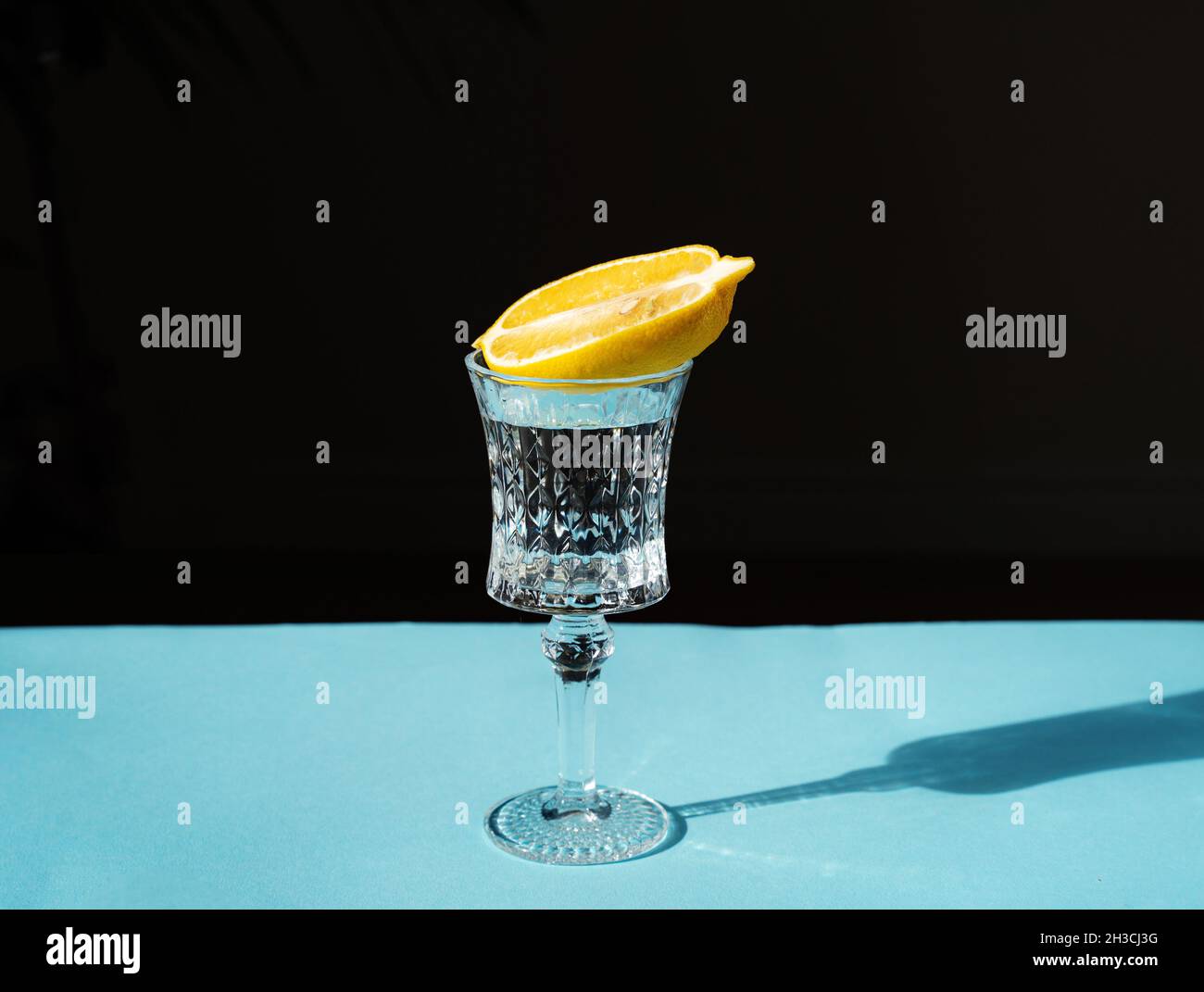 Top view of glass cap with lemon half on blue background. Sunny day ...