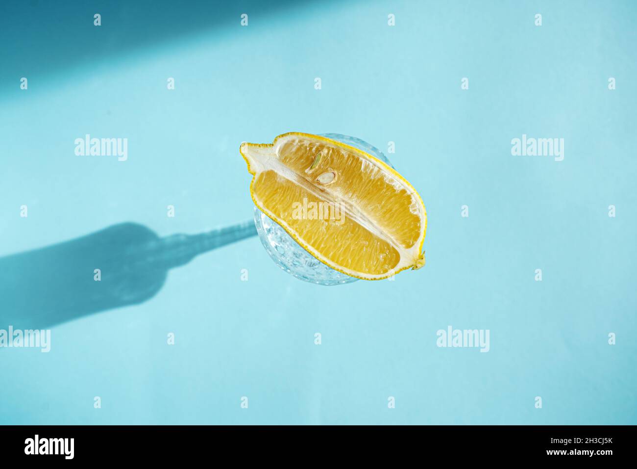 Top view of glass cap with lemon half on blue background. Sunny day ...