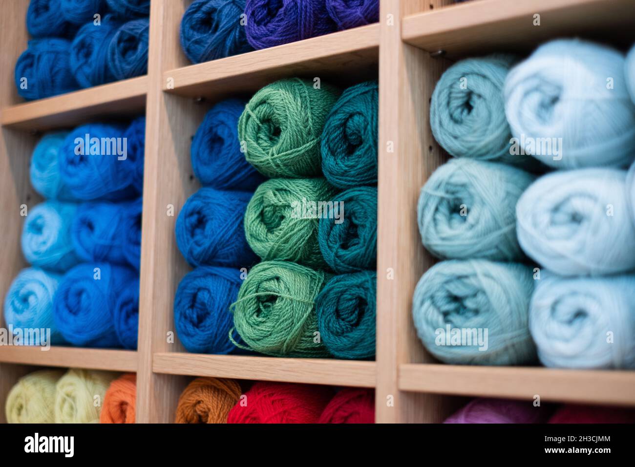 Colorful balls of yarn in shop display. Selective focus on green ...
