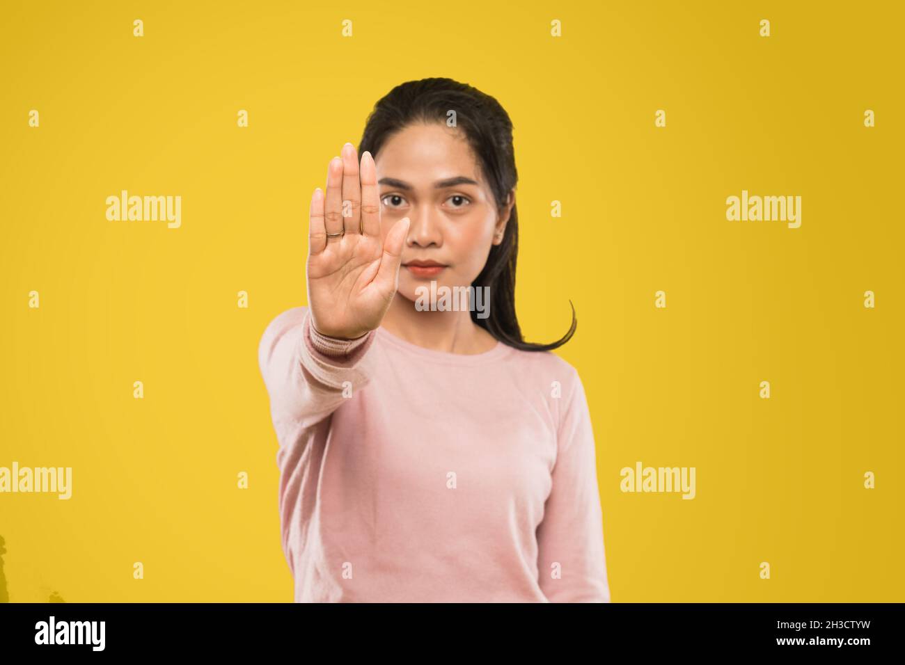 beautiful young woman with serious face with one palm movement forward ...