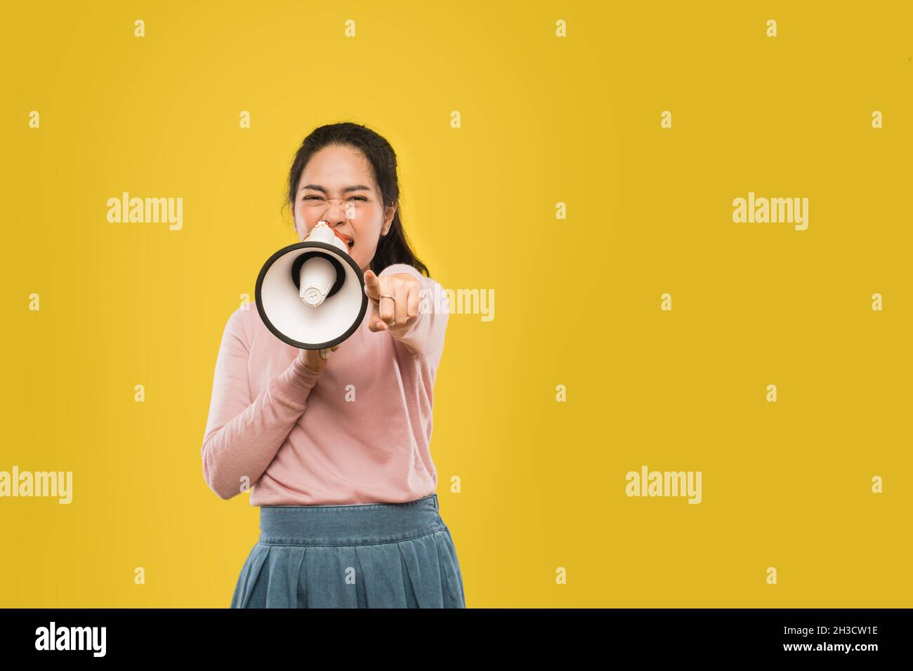 Excited beautiful woman talking seriously holding megaphone and finger ...