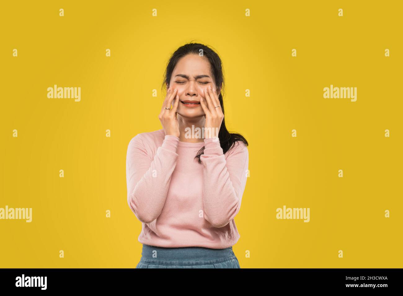 asian woman with hands holding both cheeks while crying with pain ...