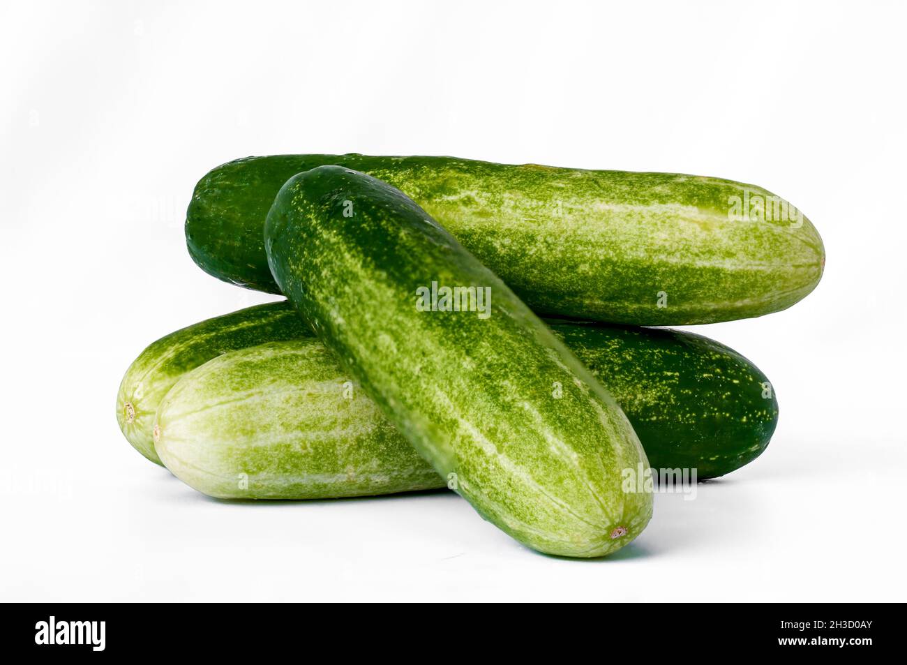 Four cucumbers for greens, in a stack composition, isolated on a white ...