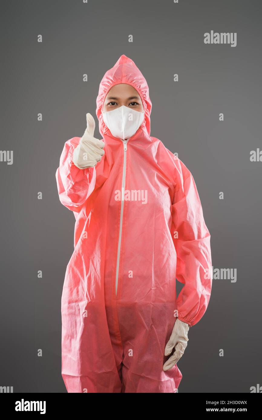 a doctor standing in red PPE and mask with thumbs up while facing front ...