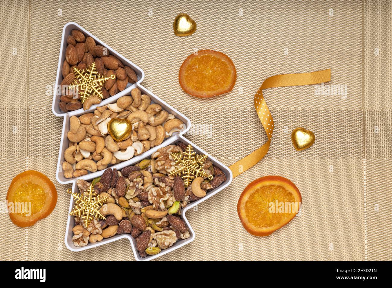 Mixed nuts and gold Christmas ornaments in a pine shape plate on ...