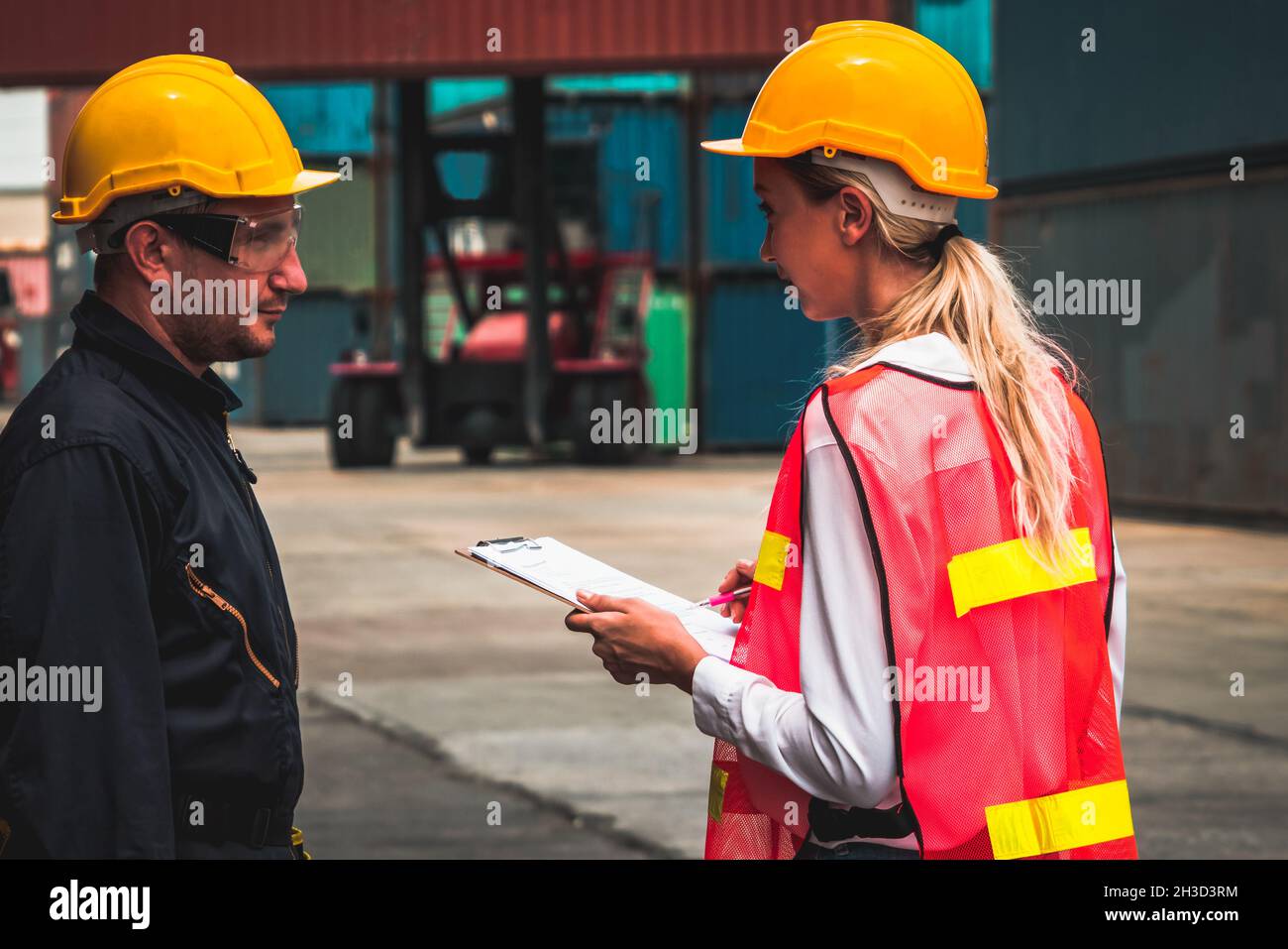 Industrial worker works with co-worker at overseas shipping container ...