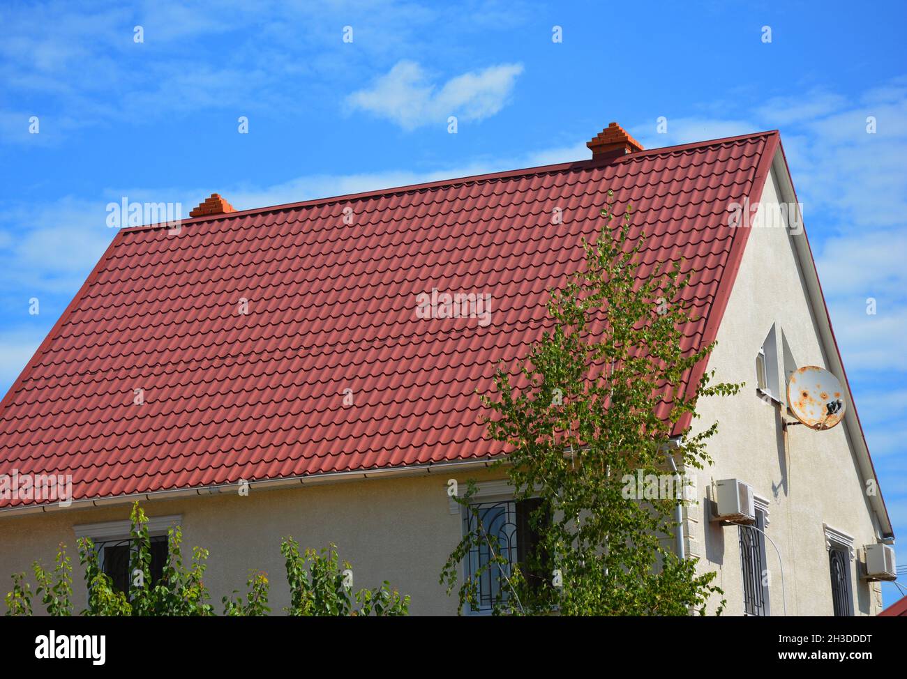 Red metal roof with roof gutter, fascia, ventilation and chimney. House ...