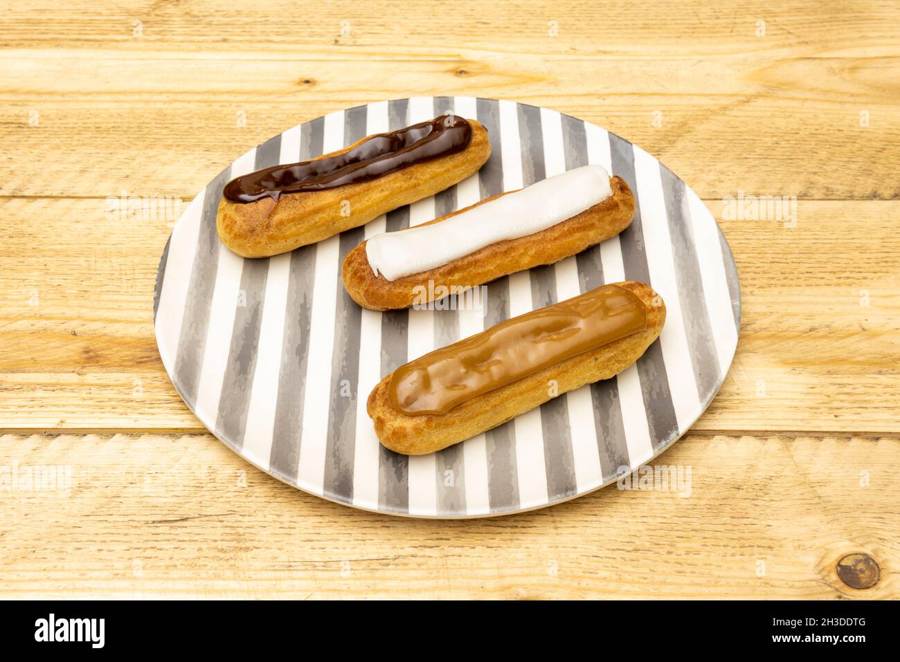 Tray of eclairs covered with three different chocolates on grated plate ...
