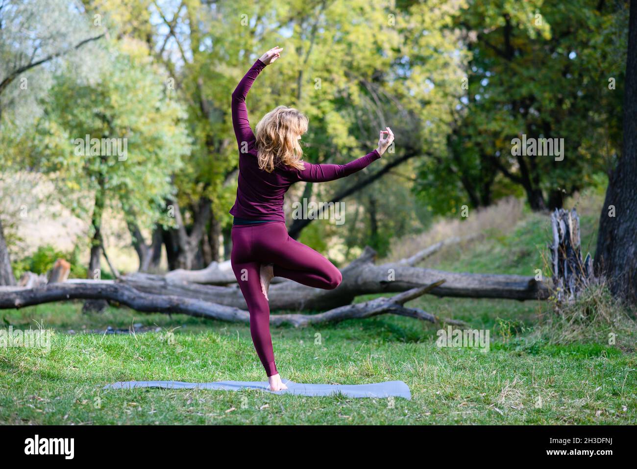 Fit woman stay back in yoga tree balance Vriksasana posture outdoors ...