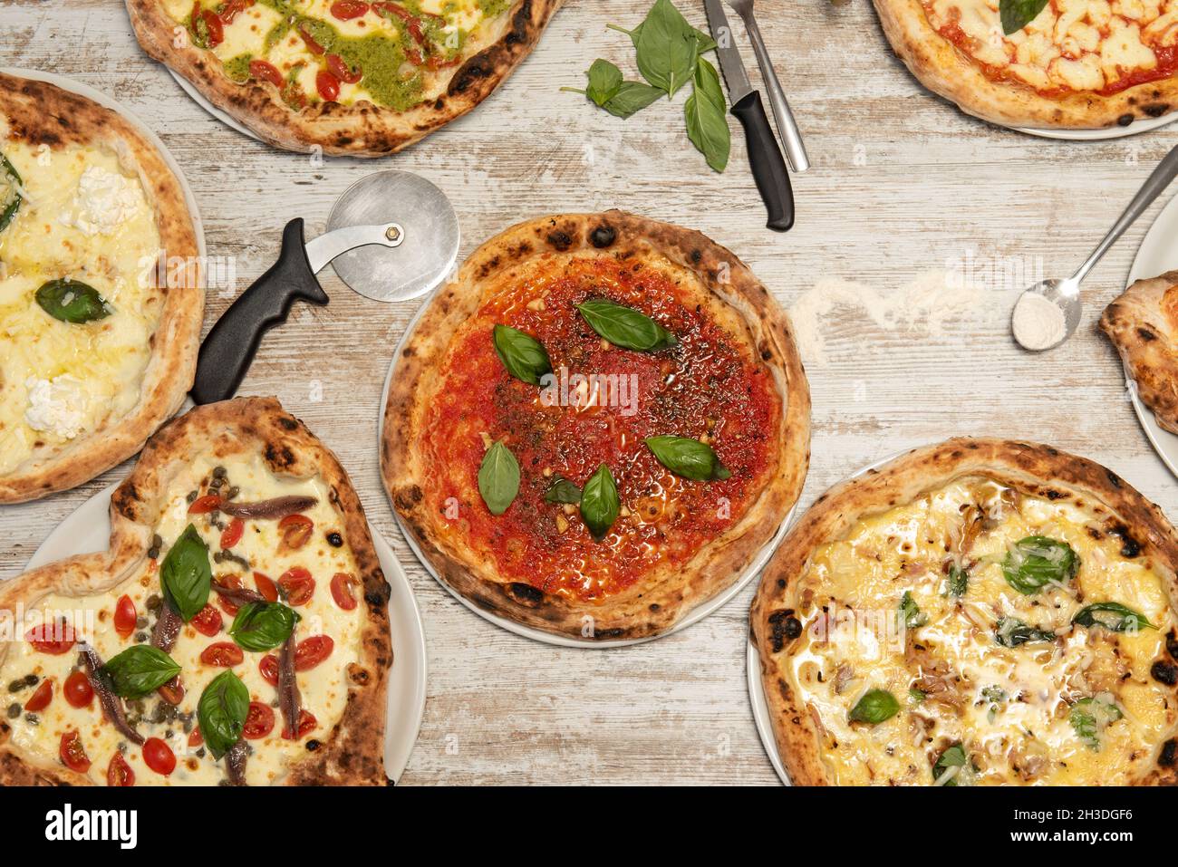 Top view image of assorted Italian pizzas with lots of basil, tomato ...