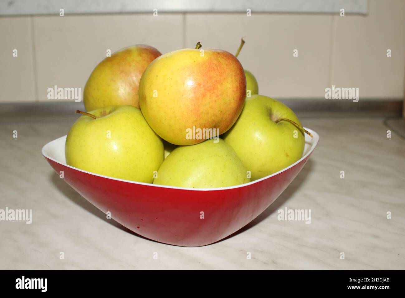 apples in a red bowl on the white kitchen counter Stock Photo - Alamy