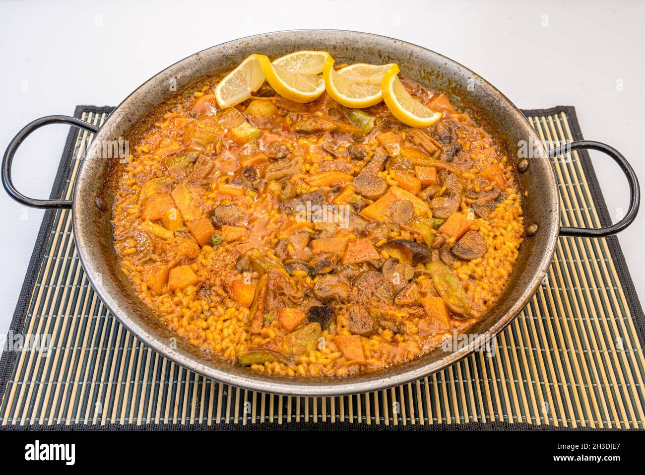 Great Spanish vegetable paella presented in its paella pan with lemon ...