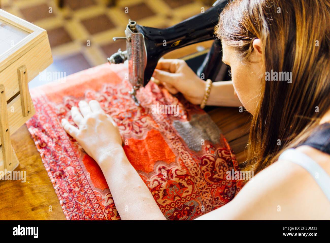 Beautiful middle-aged young woman wearing a concentrated sewing machine ...