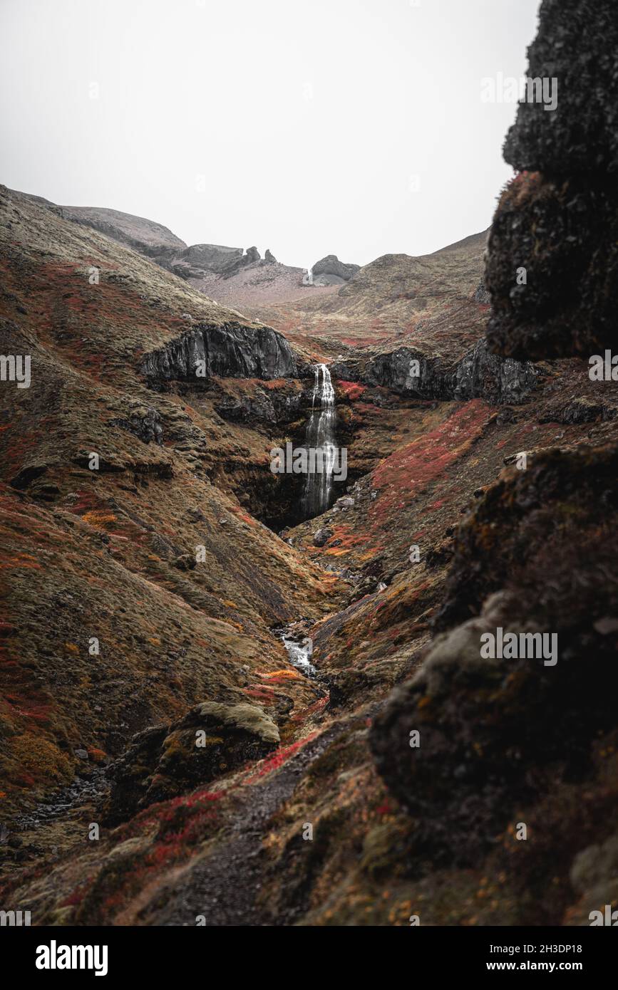 Vertical shot of a canyon with a waterfall on a gloomy day in Iceland ...