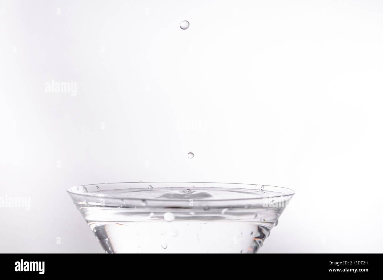 Closeup shot of water drop falling into a glass on white background ...