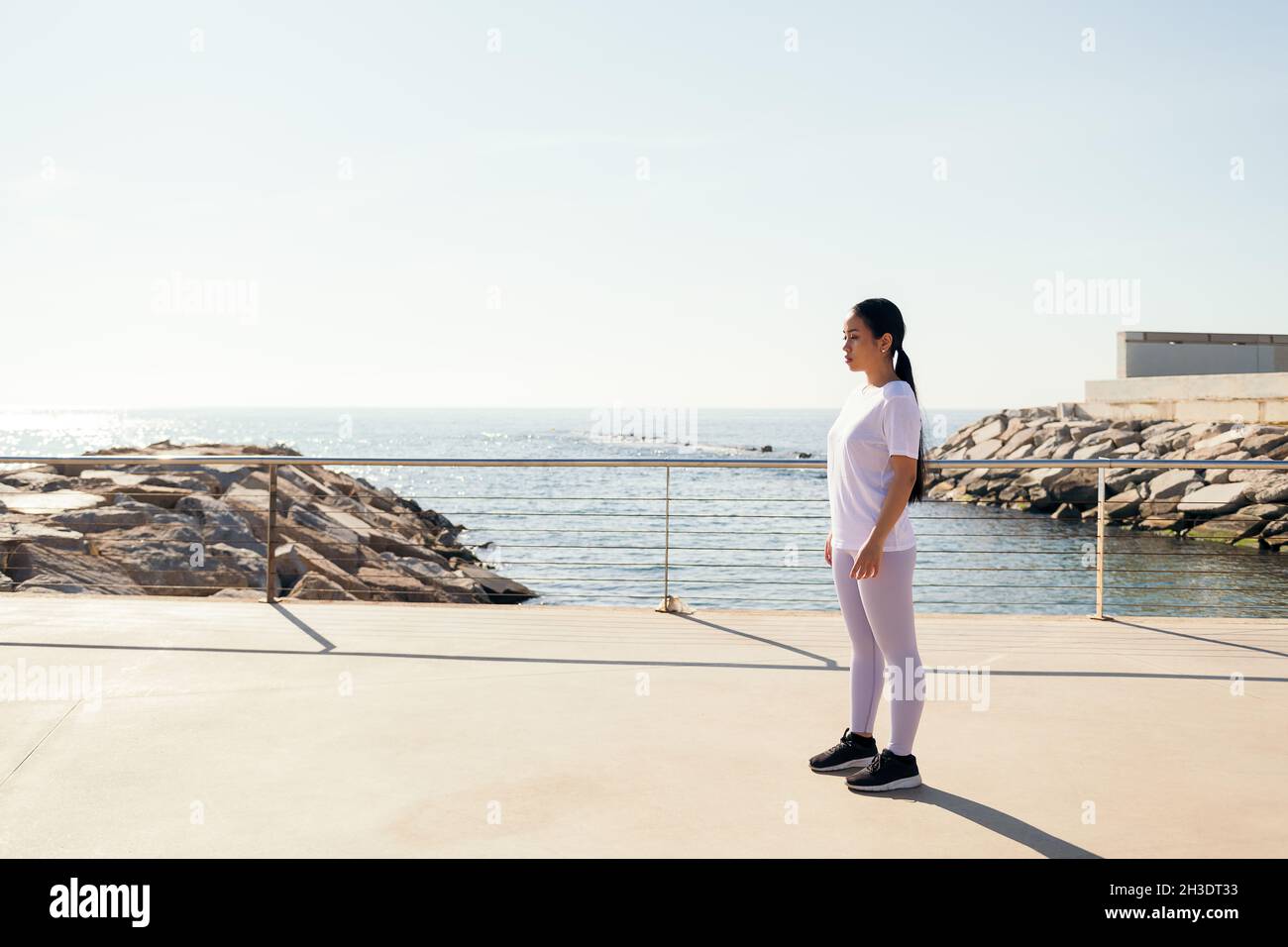 young sports woman concentrating on standing during outdoor training ...