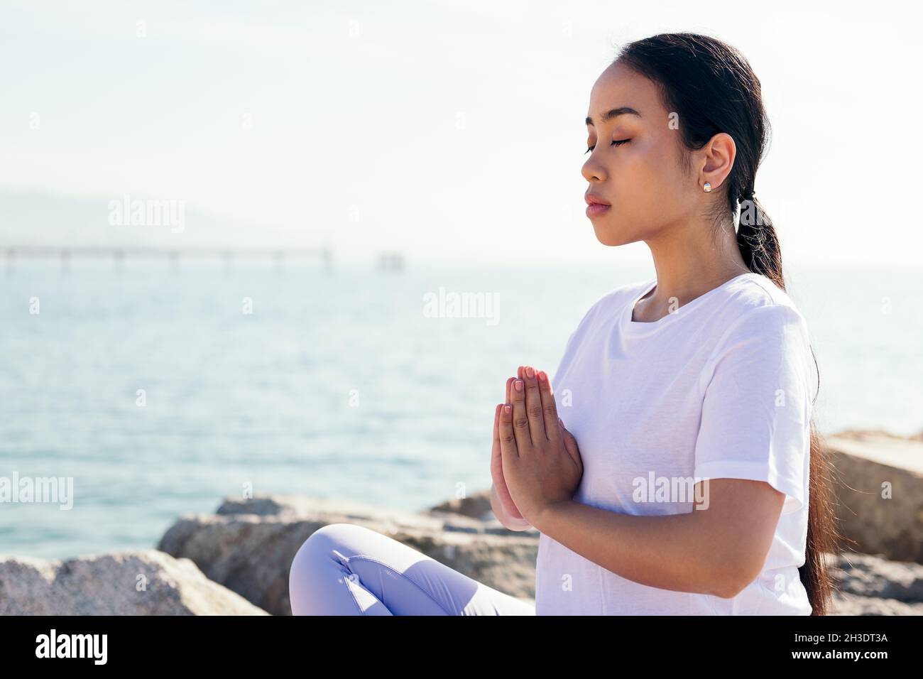 portrait of a young asian woman meditating outdoors in calm with hands ...