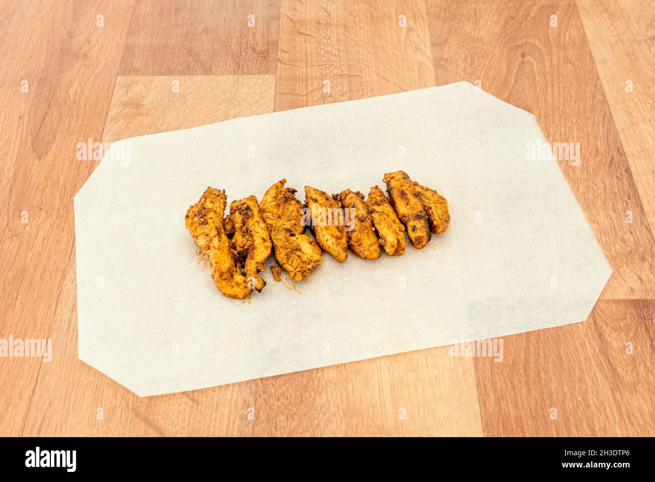 Portion of marinated and roasted chicken pieces on white greaseproof ...