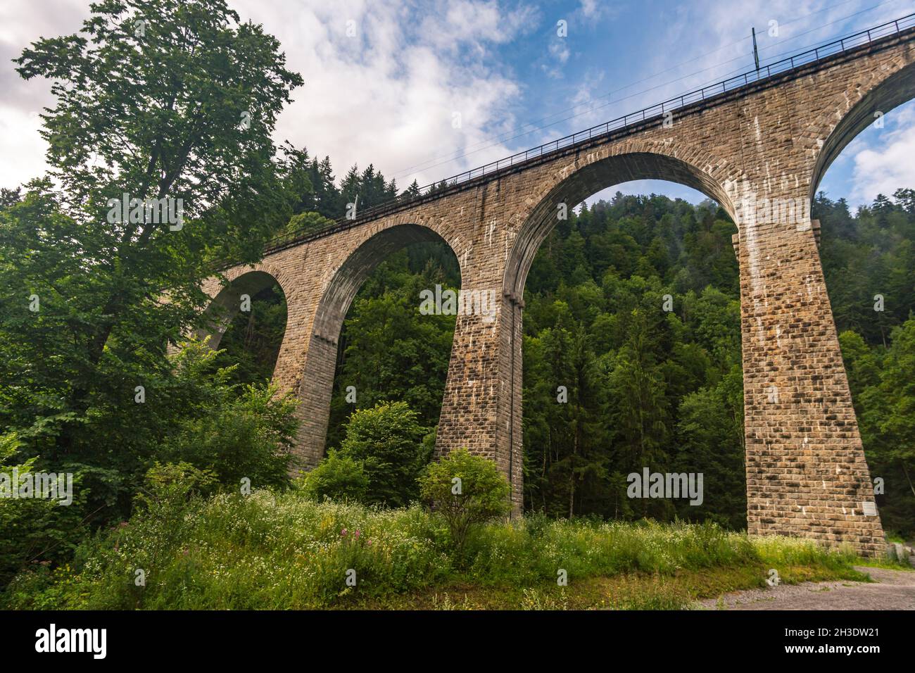 The historic railway bridge with a yellow train at the Ravenna Gorge in ...
