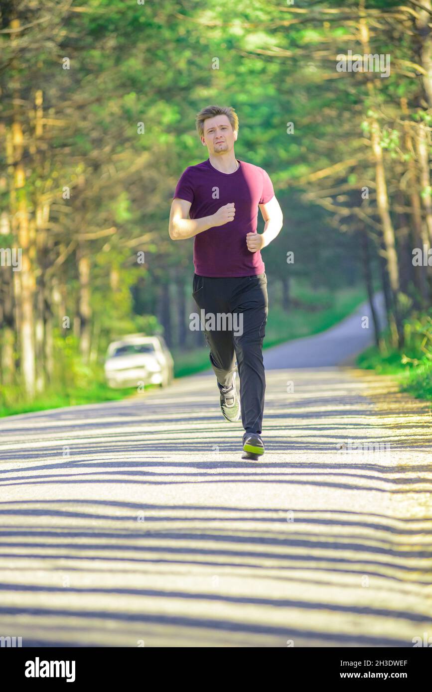 Running man jogging in city park at beautiful summer day. Sport fitness ...